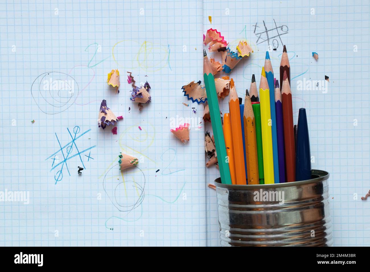 colored pencils and pens in an iron jar on the pages of a notebook as a ...