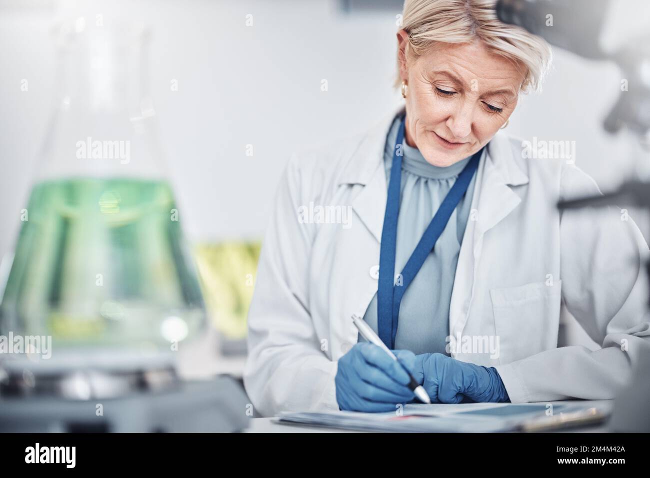 Science, research and senior woman writing notes on documents in ...