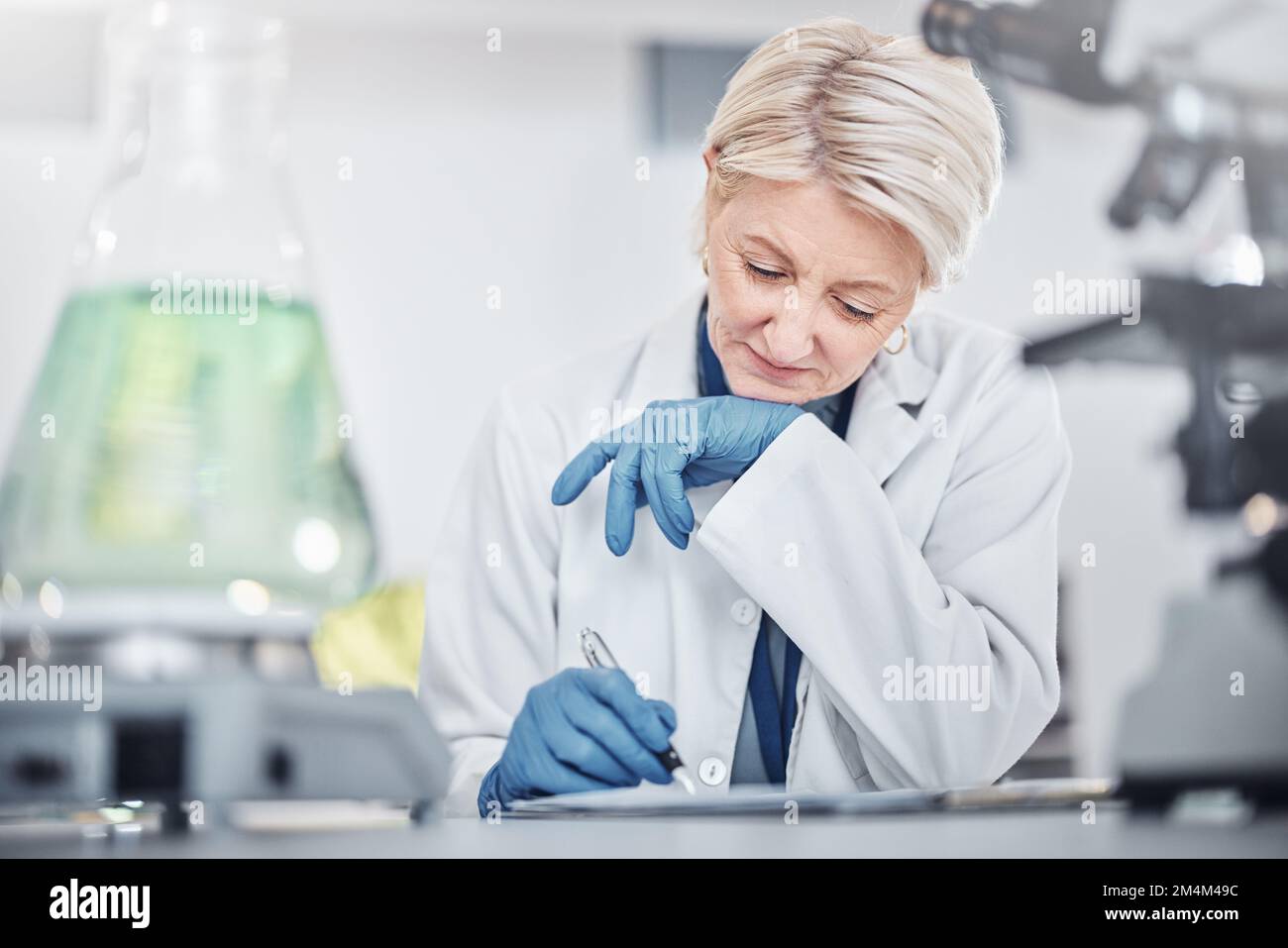 Science, research and senior woman writing notes on documents in ...