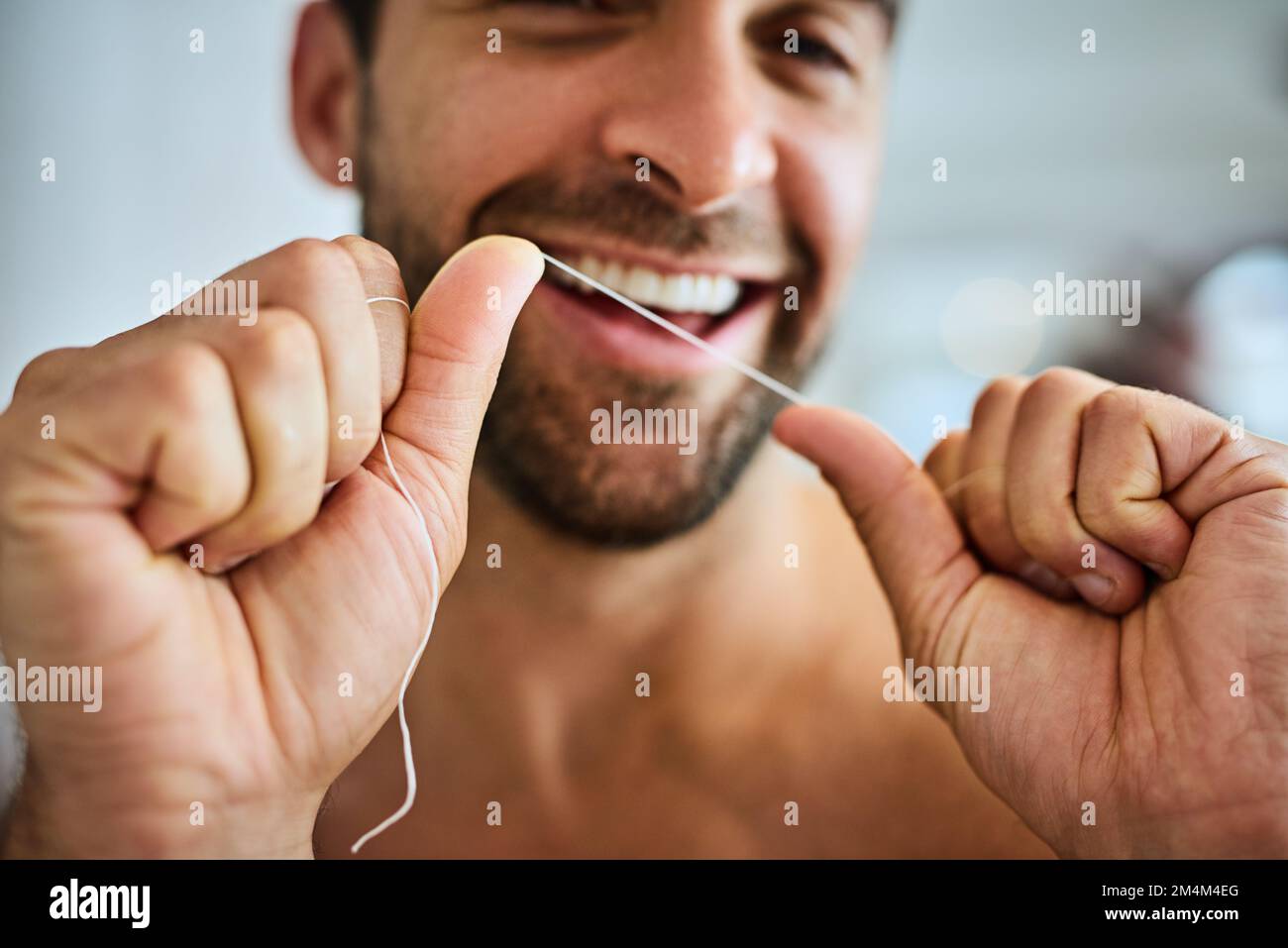 Getting my teeth completely clean. a handsome young man flossing at home Stock Photo - Alamy