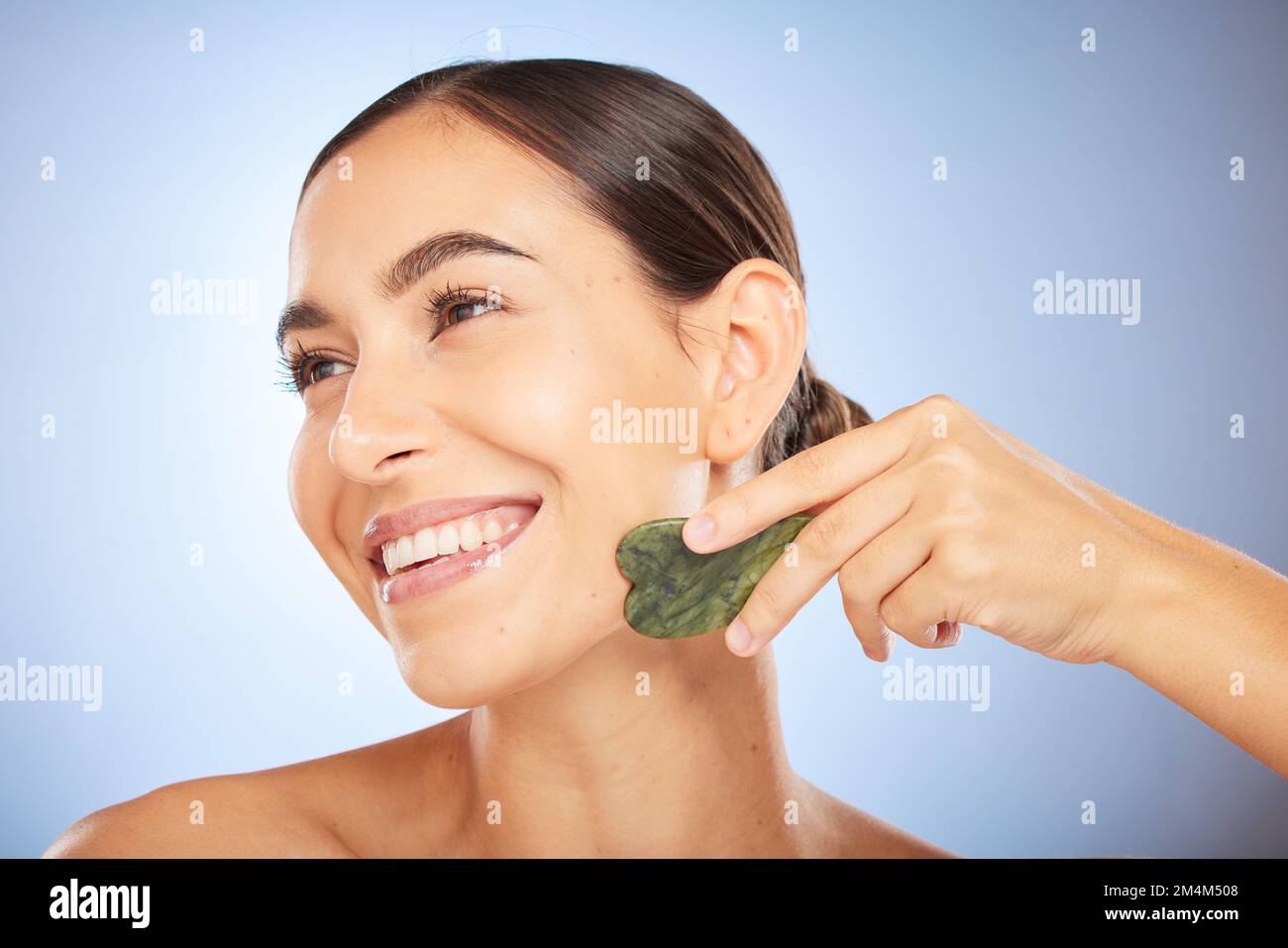 Skincare, beauty and woman with gua sha in studio on blue background ...