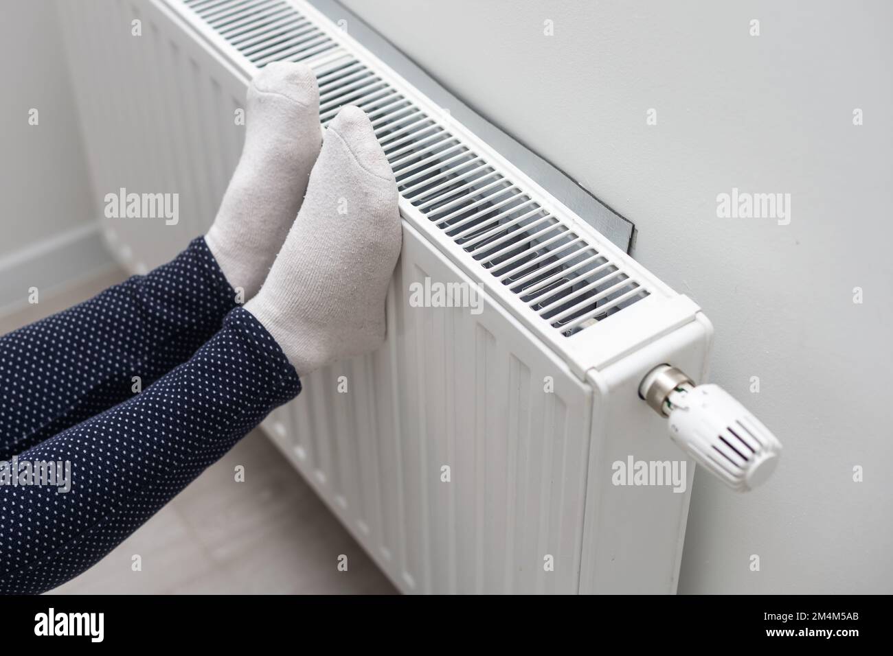 Woman warming up with feet on heater Winter socks drying on a heater ...