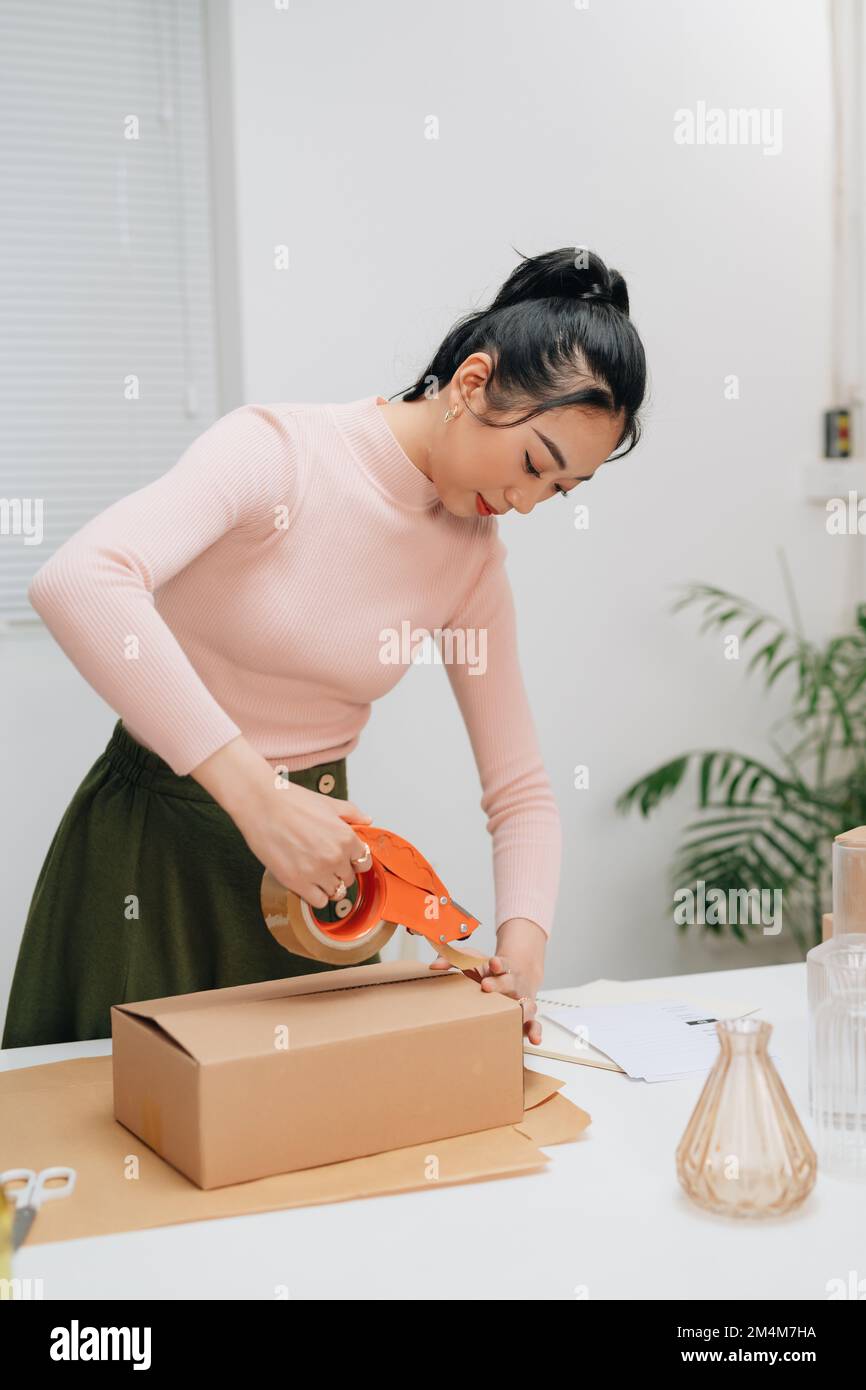 The staff is using the tape to pack the package goods to the customer ...