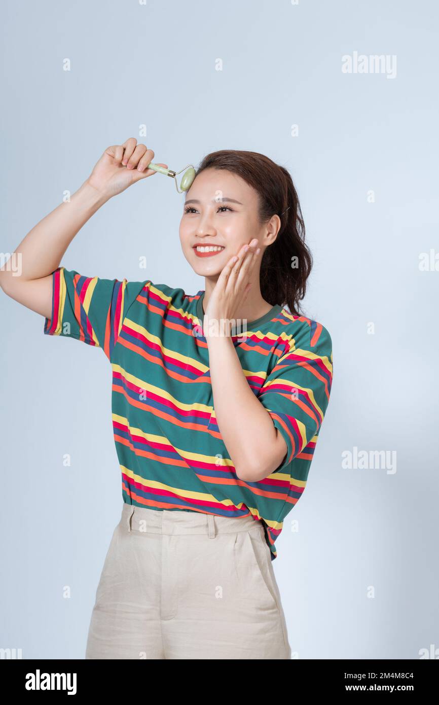 Woman routine roller massage on face in apartment. Daily body skin care ...