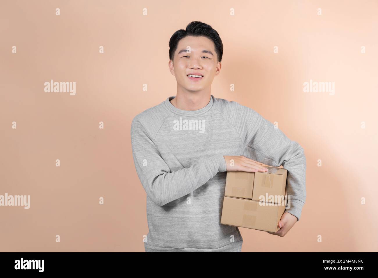 man carrying boxes, smiling on beige background Stock Photo - Alamy