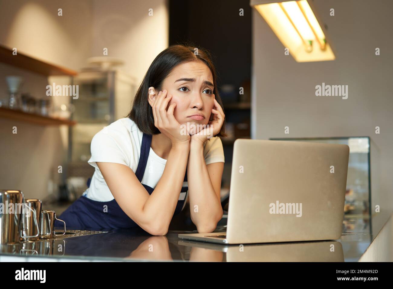Asian girl barista, standing behind counter in cafe, looking as at ...