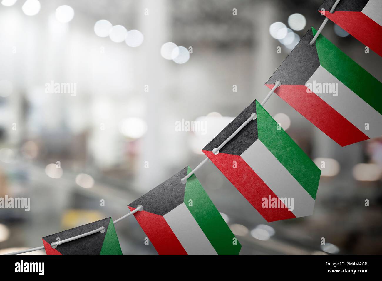 A garland of Kuwait national flags on an abstract blurred background ...