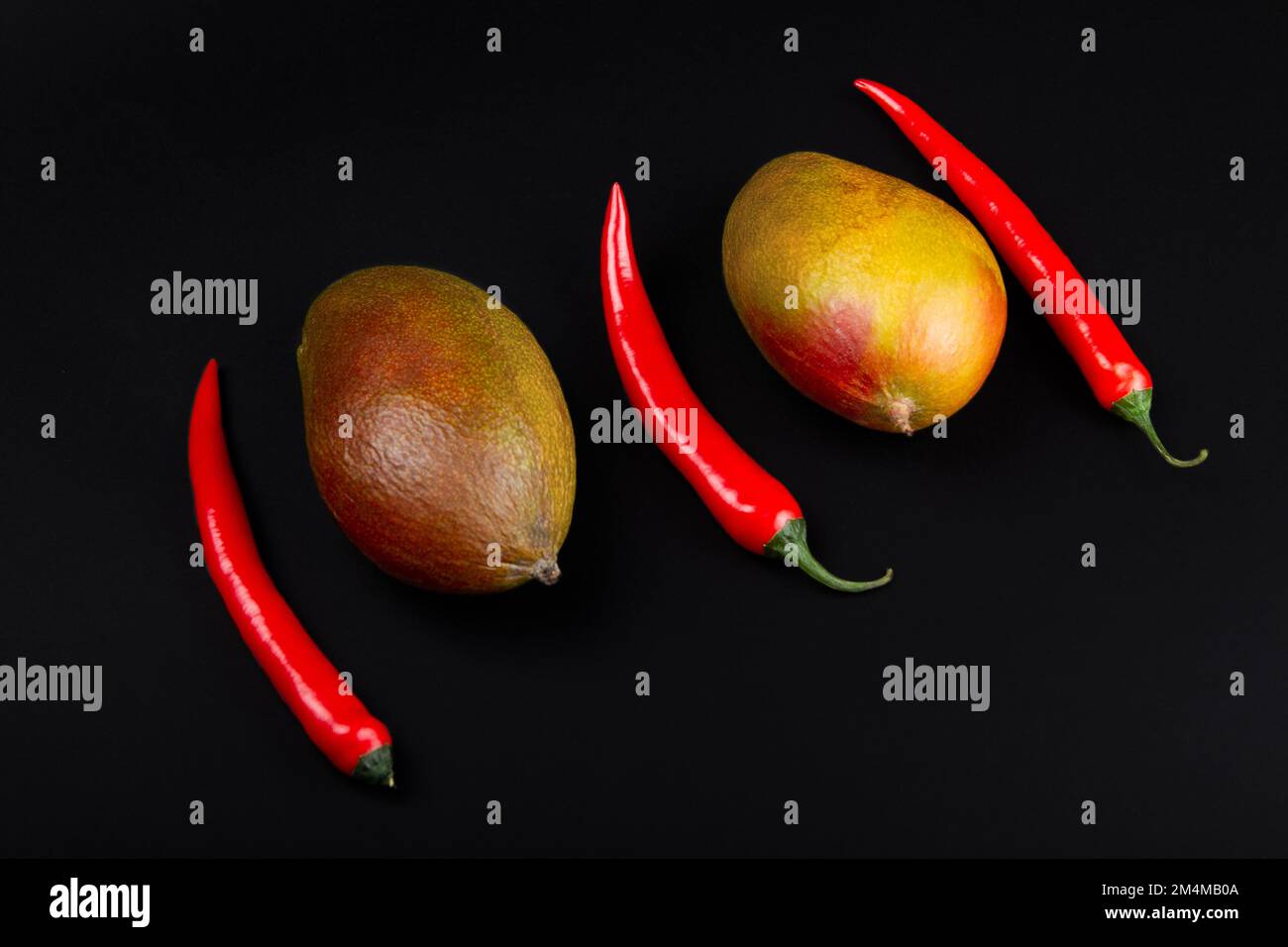 Whole mangoes and chili on black background. Ingredients for Spicy ...