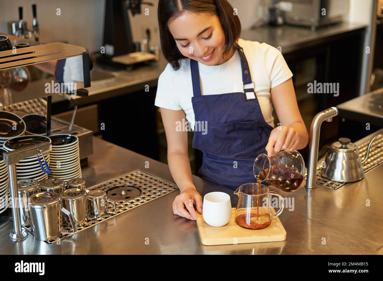 Barista in cafe pouring filter coffee, brewing and preparing order ...