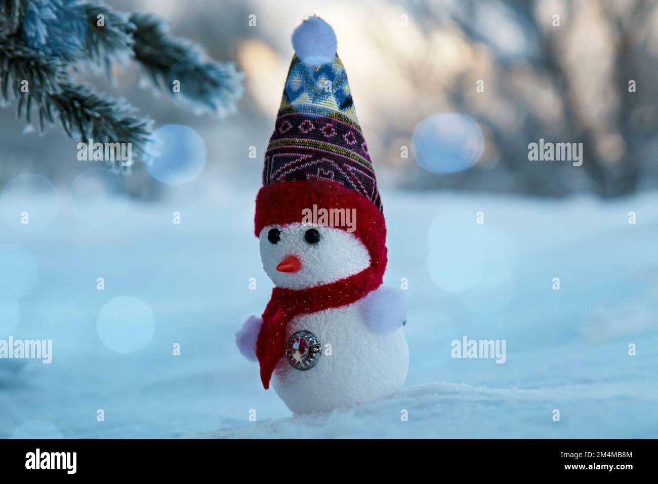 A snowman stands under a Christmas tree in the snow. Christmas toy ...