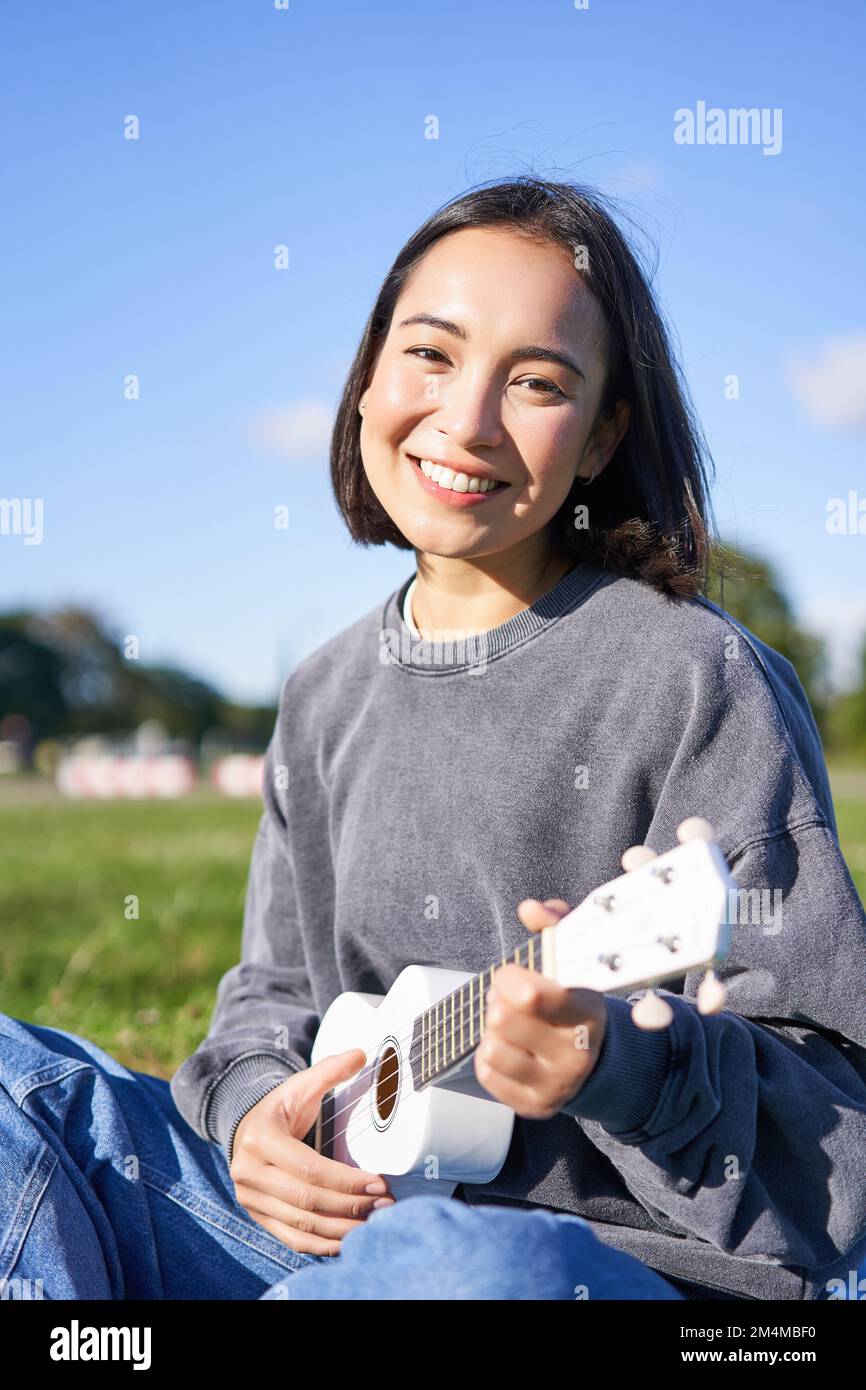 Portrait Of Cute Smiling Girl Playing Ukulele In Park Young Woman With