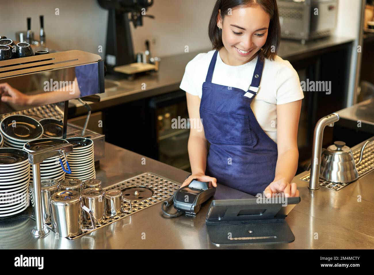 Smiling asian girl barista working in cafe at counter, processing ...