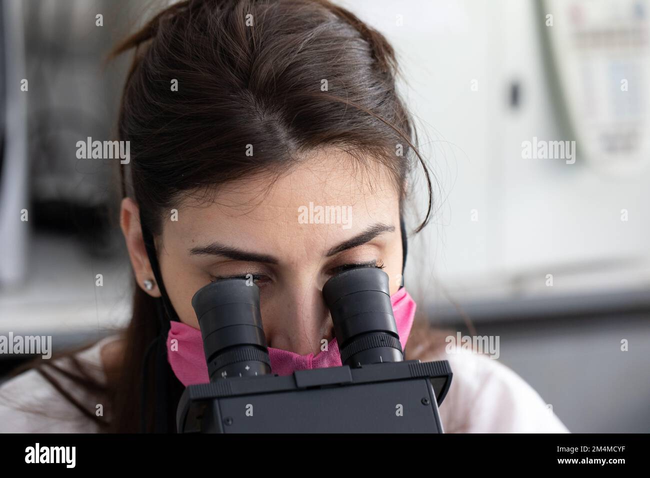 Laboratory assistant eyes looking at microscope wearing mask Stock ...