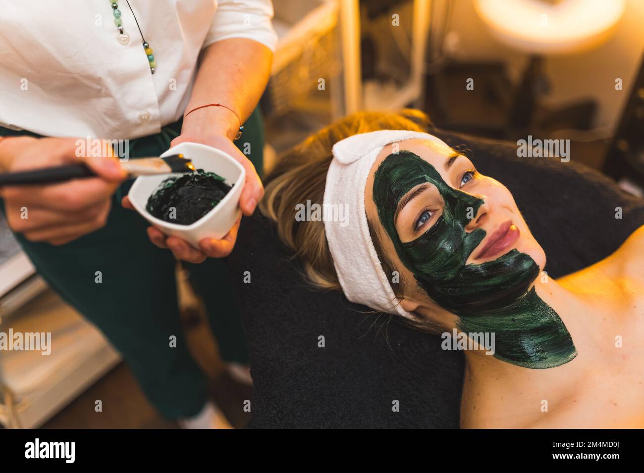 Female SPA client with half of face covered in black mask. Beauty and ...