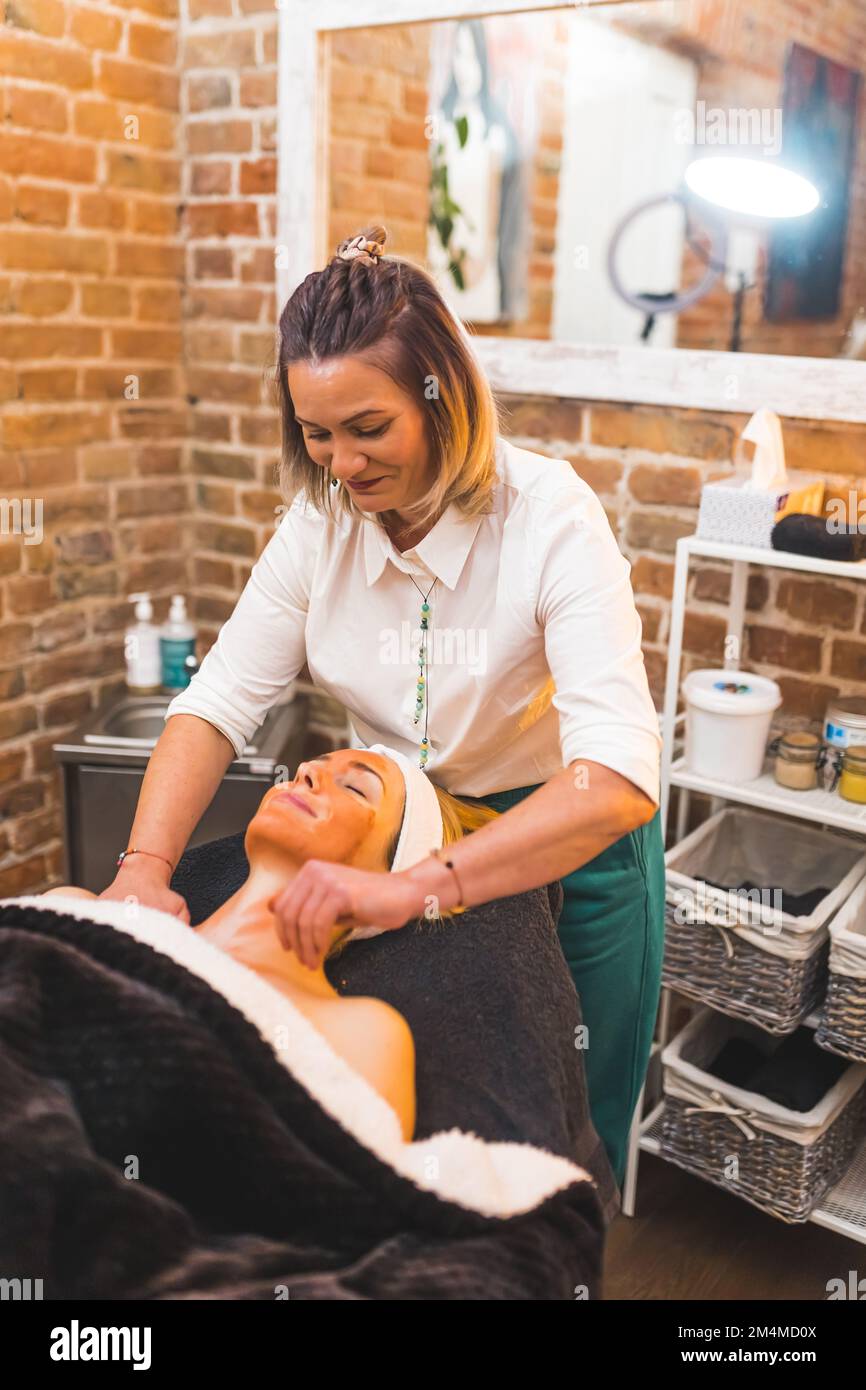 Professional Smiling Caucasian Massage Therapist Doing Facial Procedure And Massaging The Neck