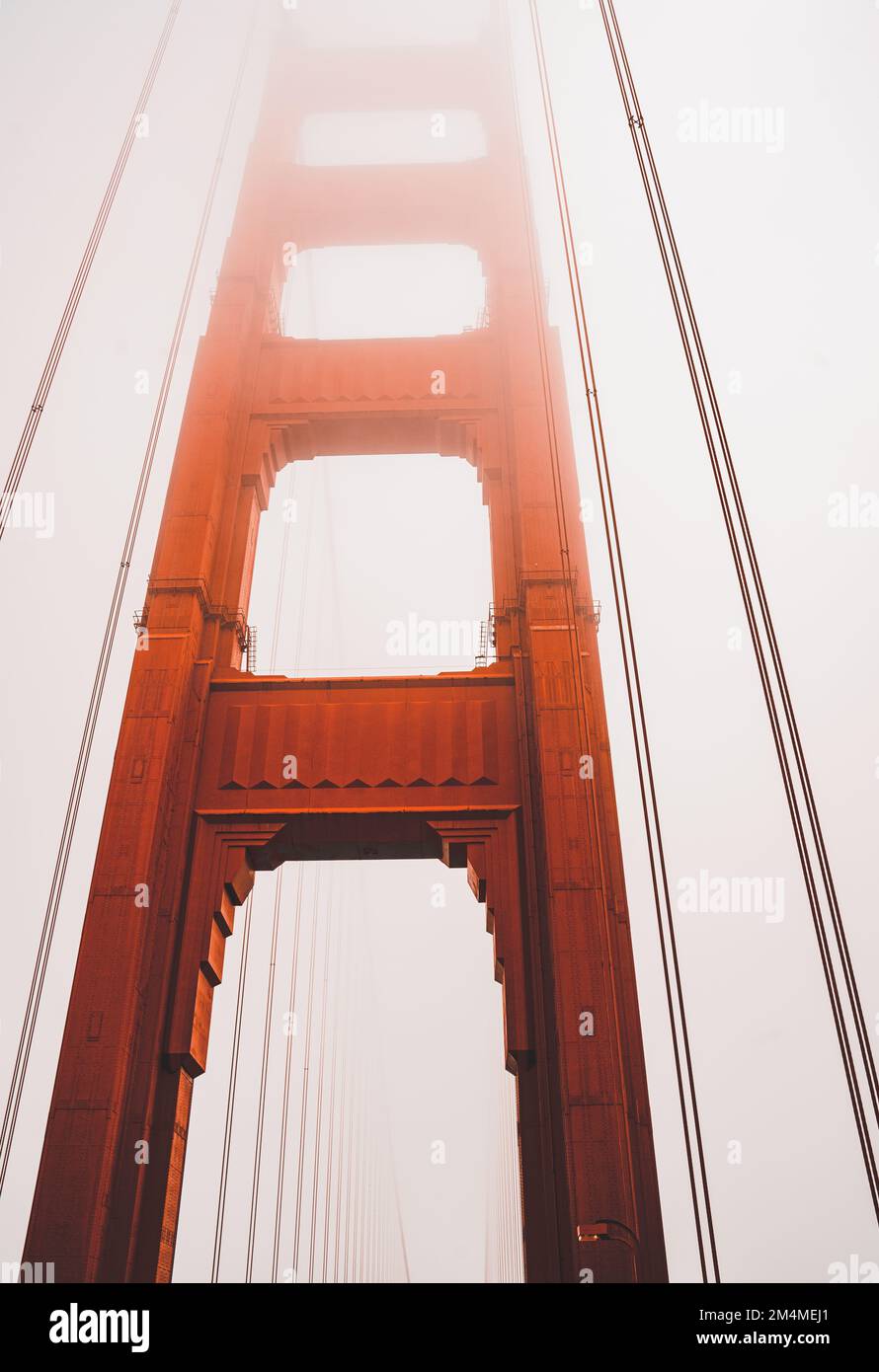 A vertical low-angle partial view of Golden Gate Bridge on a foggy day ...