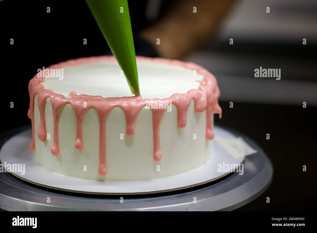 cake chef designer preparing dripping on white frosted cake for baby ...