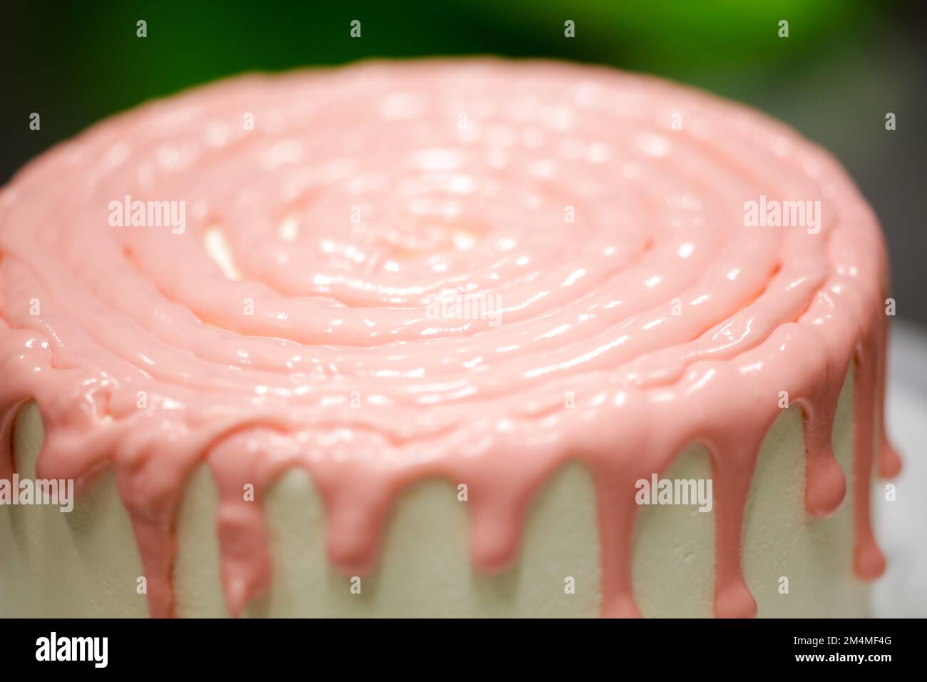 cake chef designer preparing a pink dripping on white frosted cake for ...