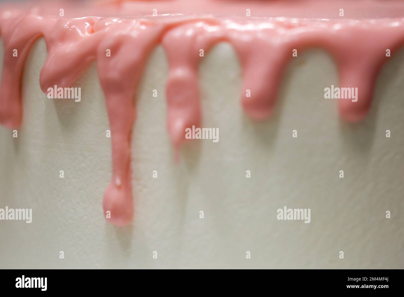 cake chef designer preparing a pink dripping on white frosted cake for ...