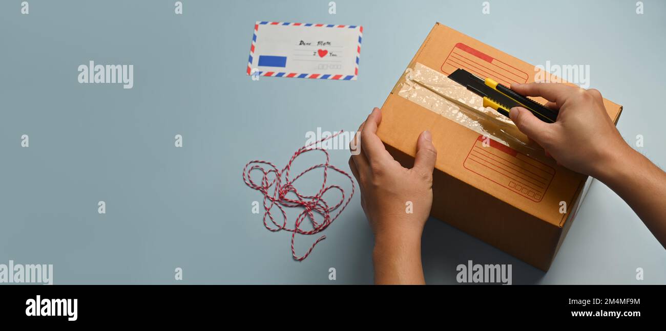 Overhead view of man cutting a cardboard box with sharp cutter knife ...