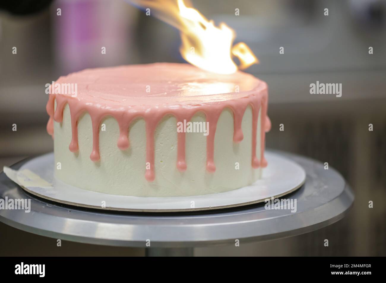 cake chef designer preparing a pink dripping on white frosted cake for ...