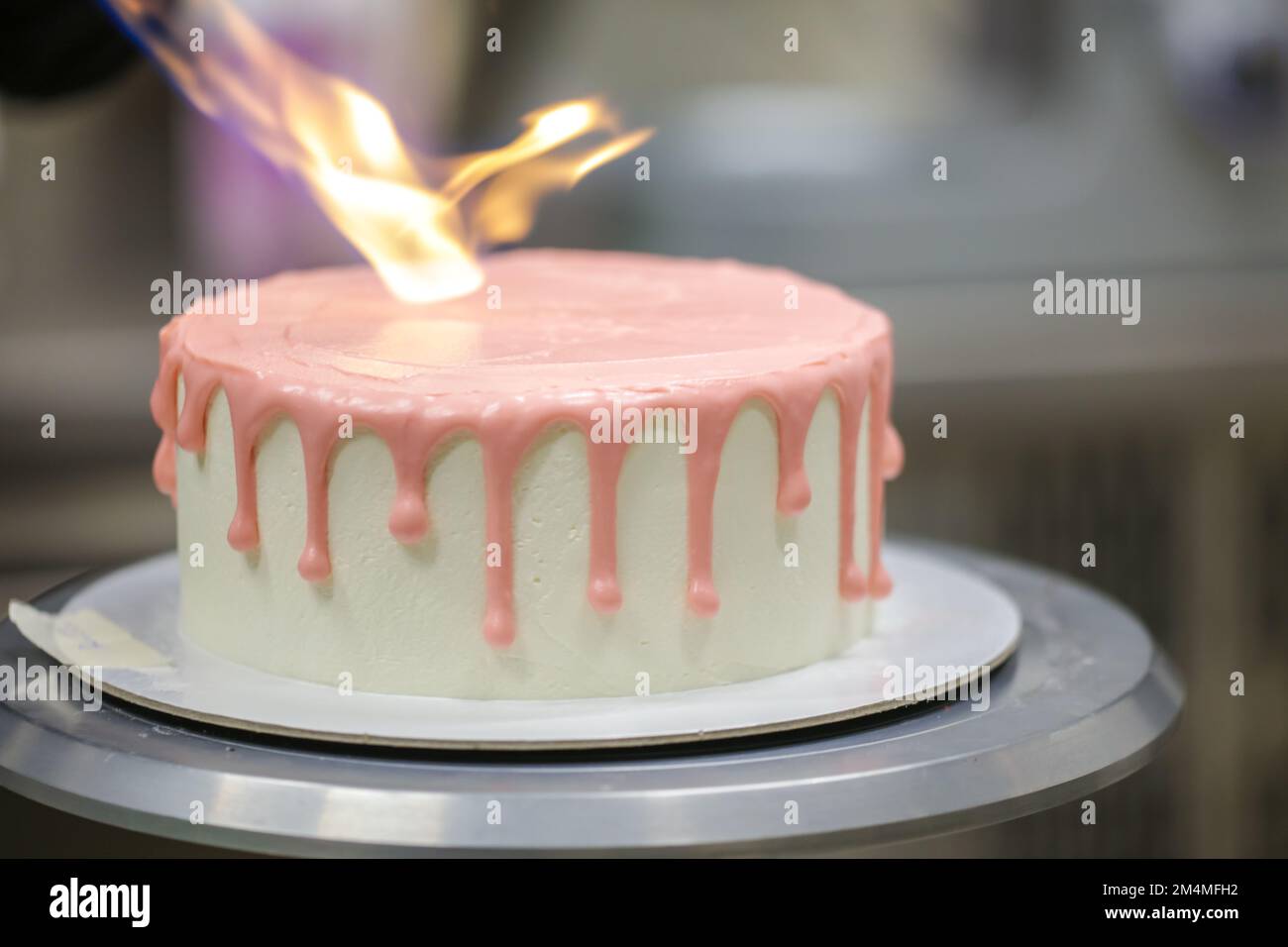 cake chef designer preparing a pink dripping on white frosted cake for ...