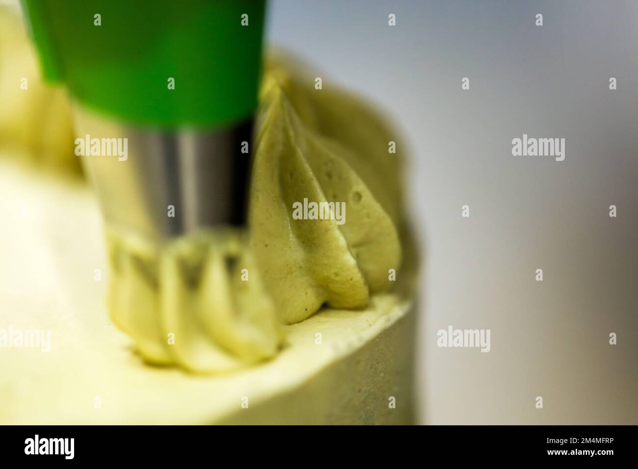 pastry chef designer making swirls with piping bag pistachio cream ...