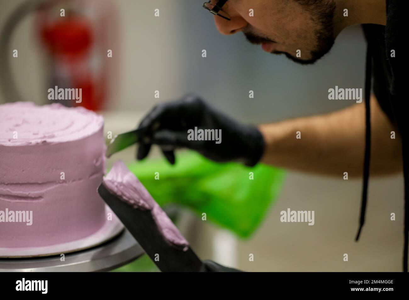 pastry chef using spatula and scraper smoothing levelling layered lilac ...