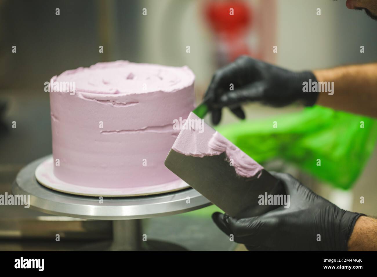 pastry chef using spatula and scraper smoothing levelling layered lilac ...
