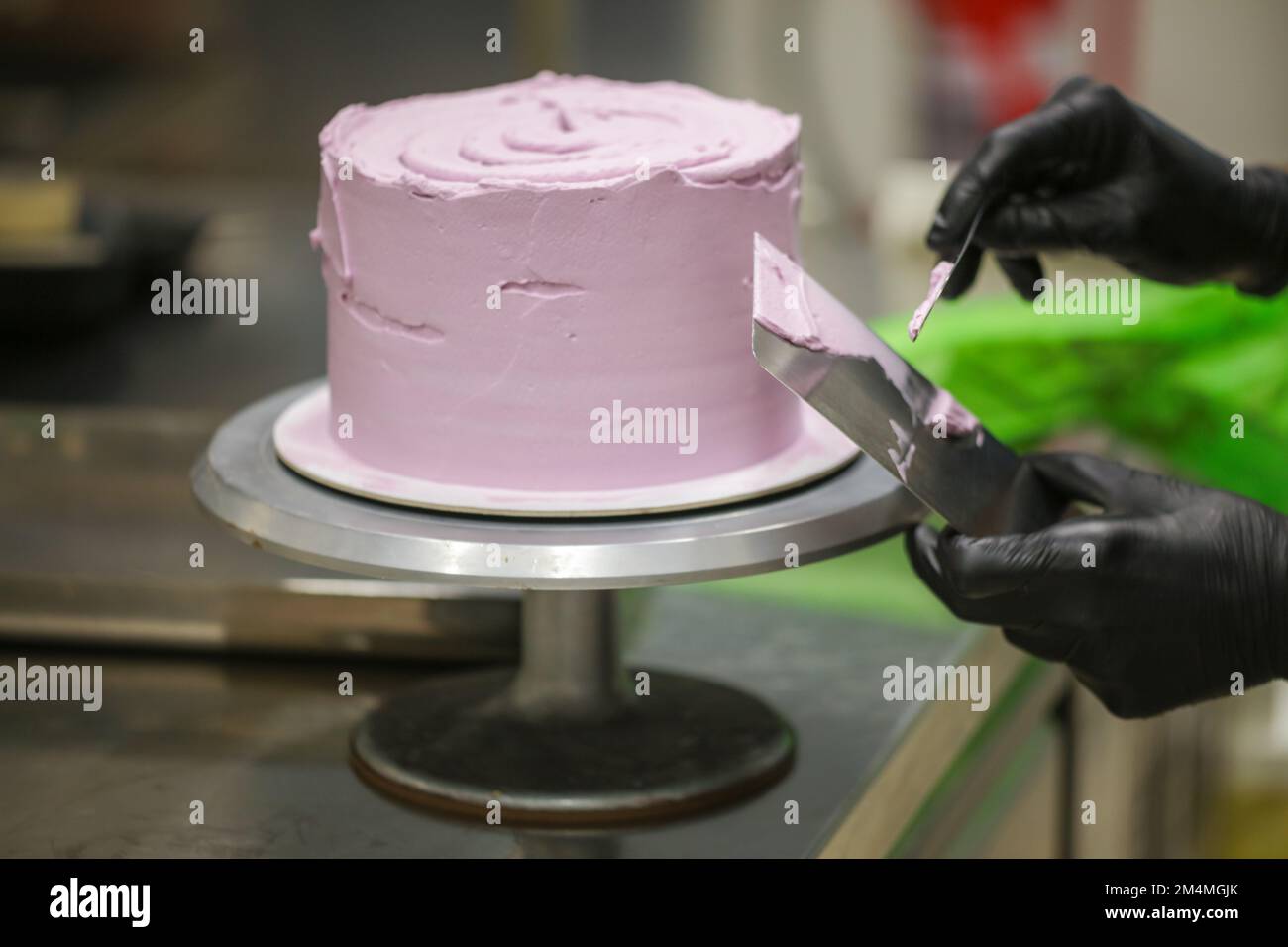 pastry chef using spatula and scraper smoothing levelling layered lilac ...