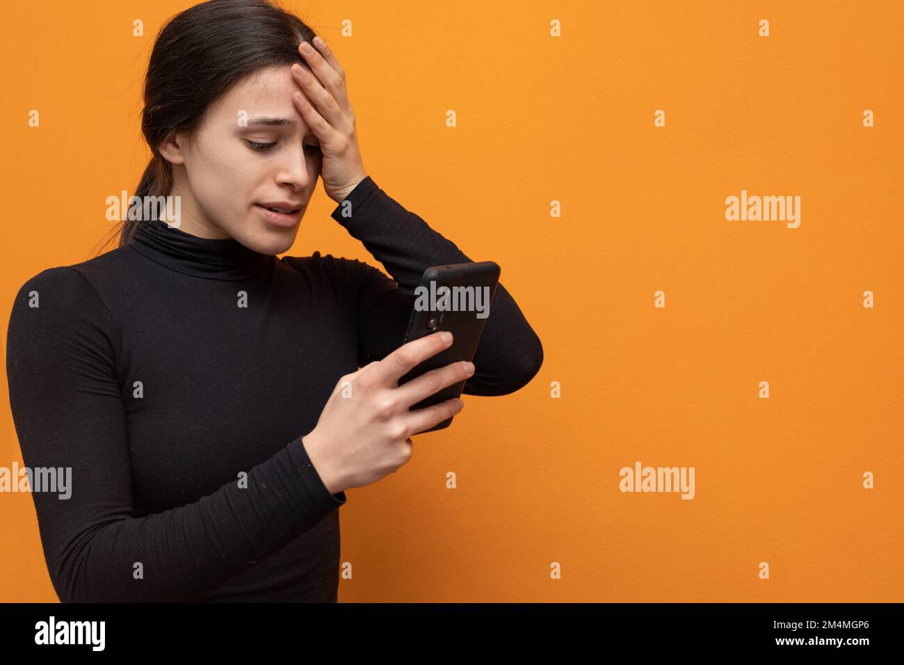 Young caucasian woman hold and look at phone in despair worried ...