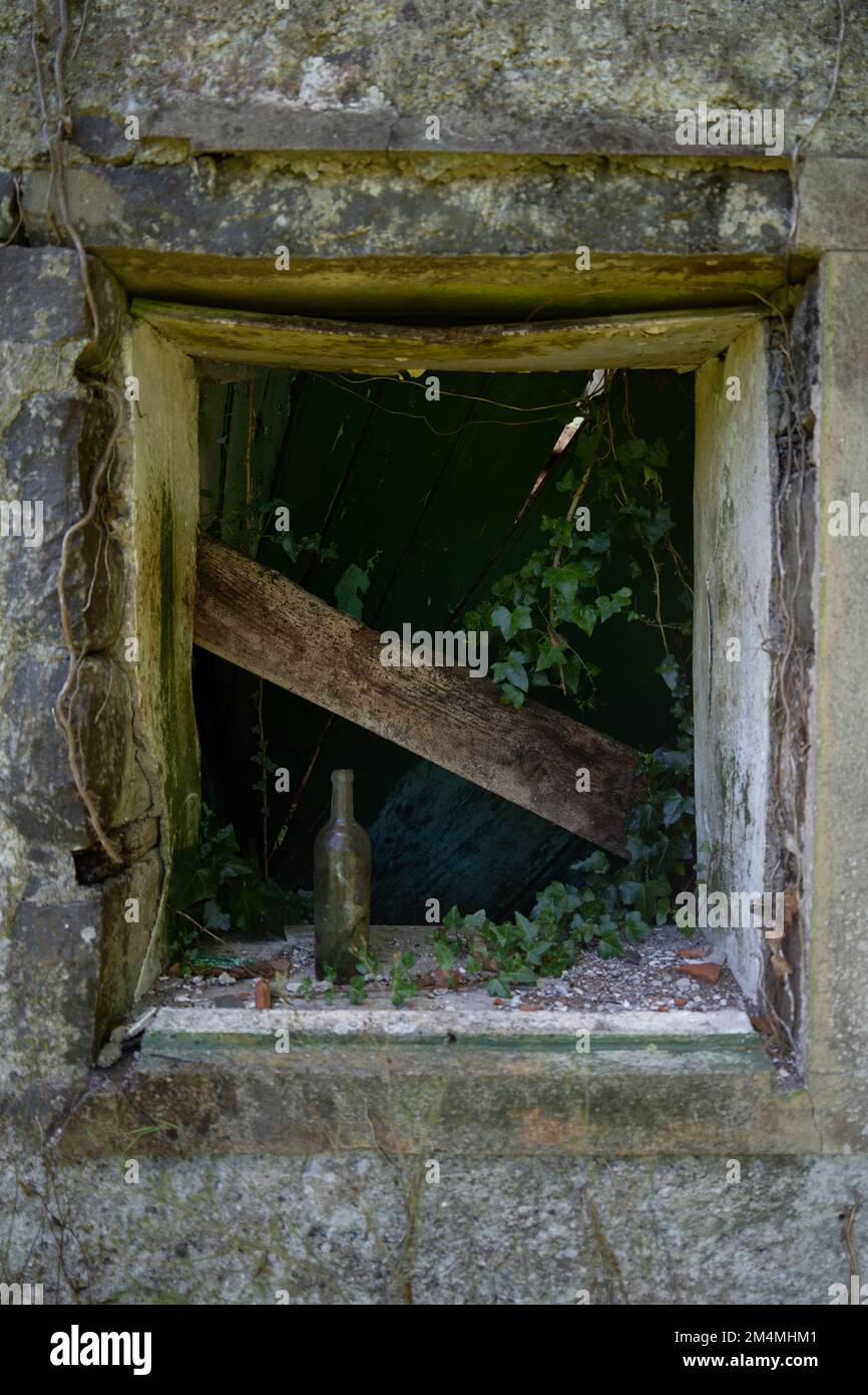 A vertical shot of a lookout window of an abandoned place with bottle ...