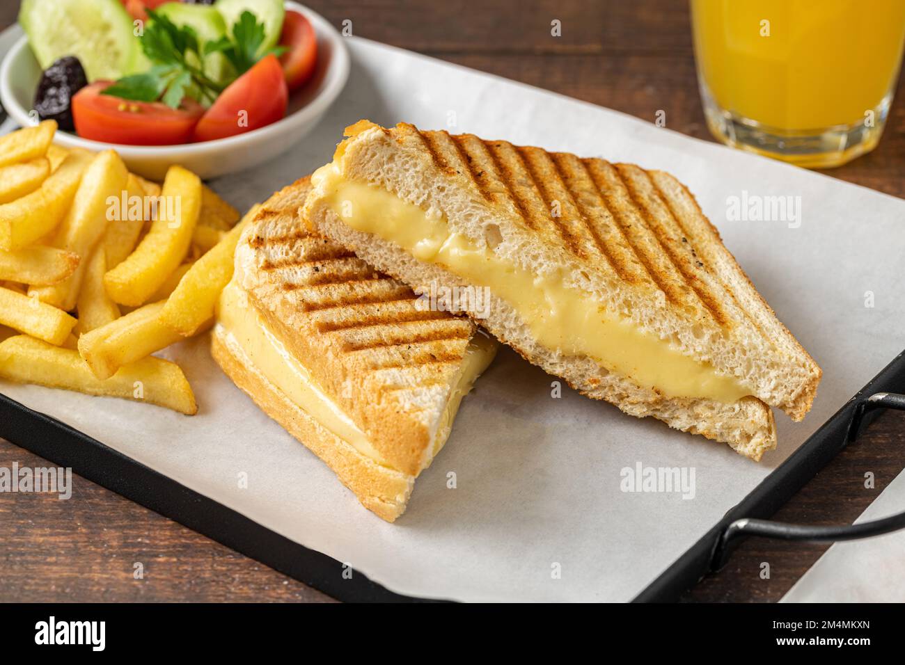 Cheddar cheese toast with french fries and salad on wooden table Stock ...