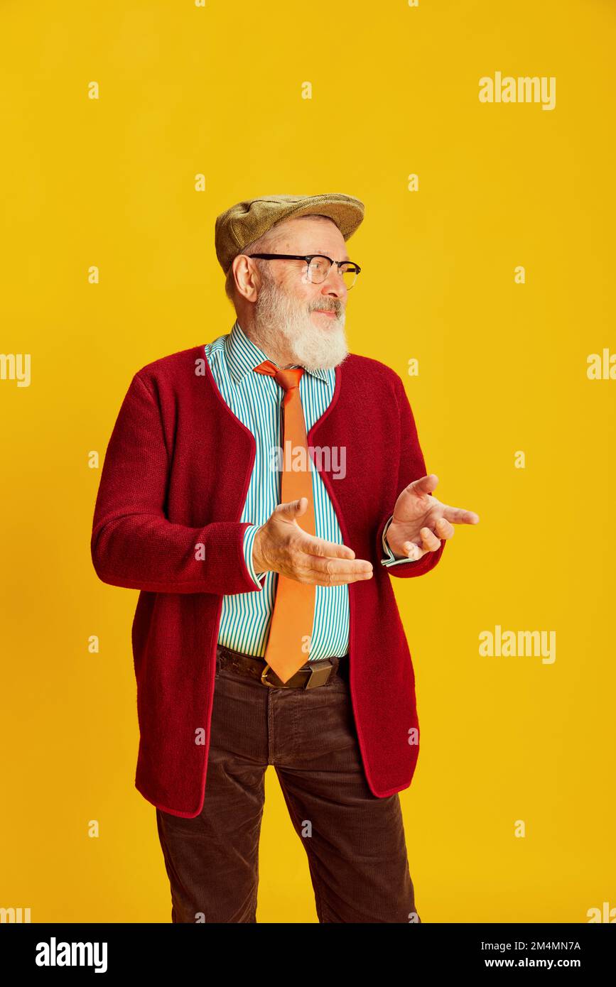 Portrait of senior man in classical clothes, glasses and cap posing ...