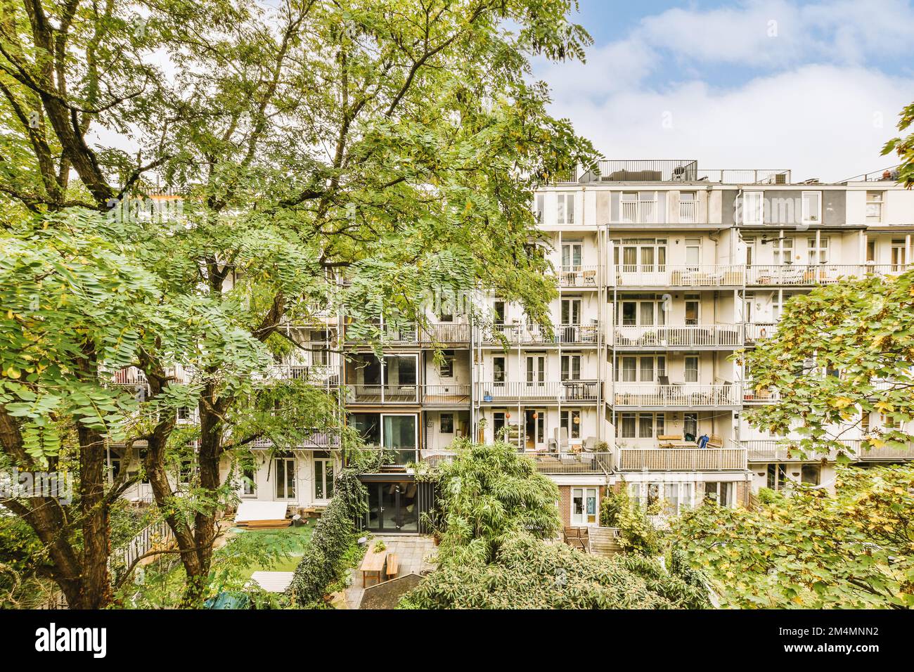 an apartment complex with trees and bushes in the foreground area ...