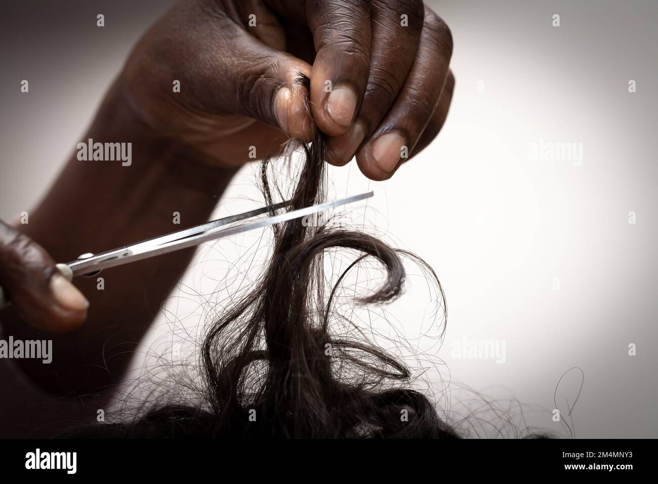 Closeup of an African woman's hands cutting a lock of a child's hair ...
