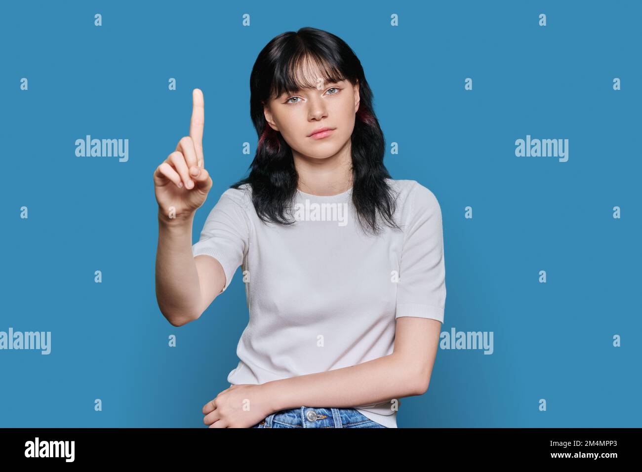 Serious young woman showing index finger up, over blue background Stock ...