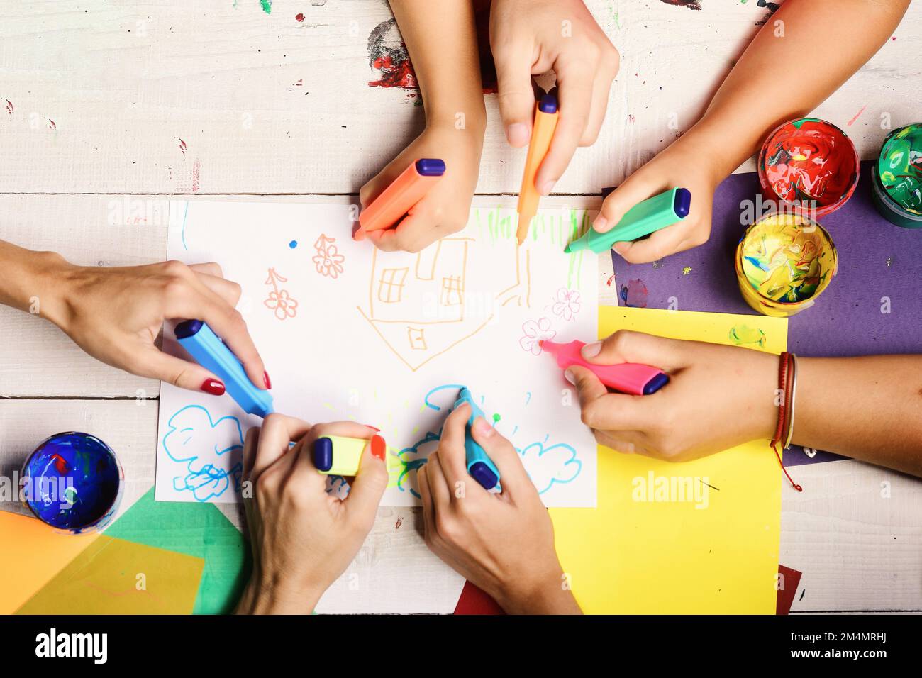 Artists wooden table with paints and colored paper Stock Photo - Alamy