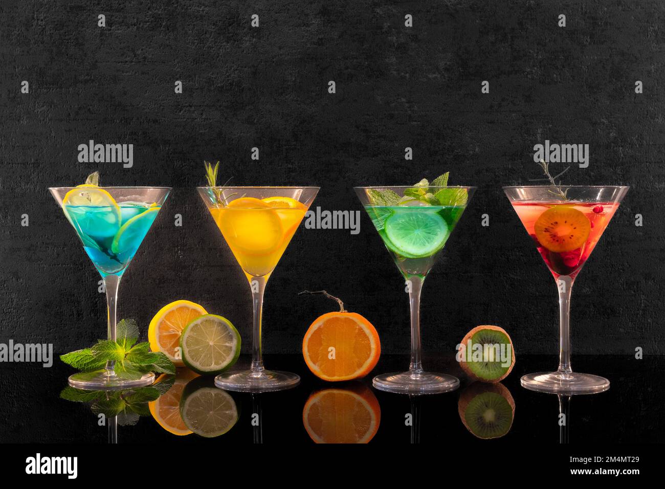 Four different cocktail glasses with colored cocktails on a black ...
