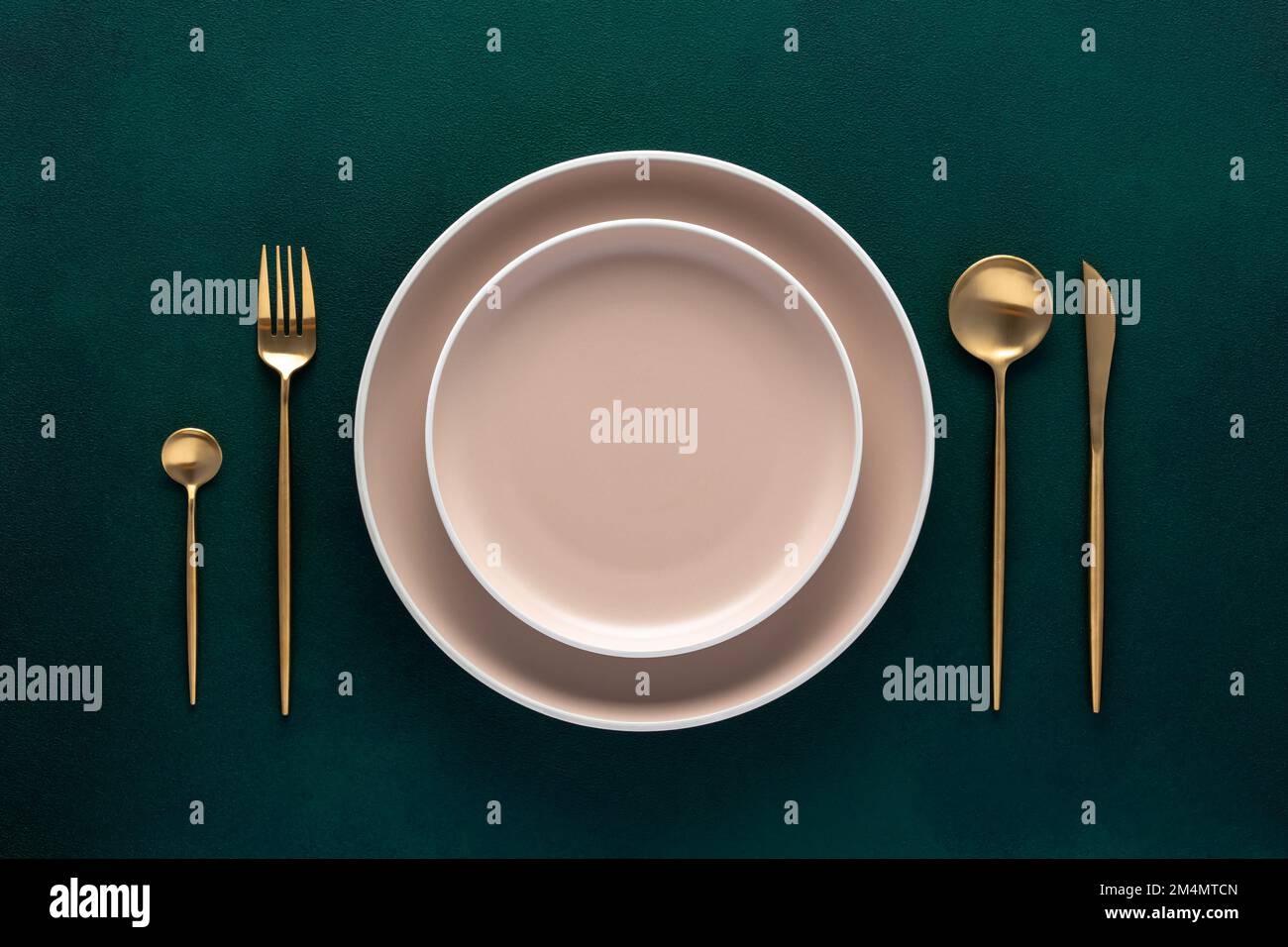 Festive place setting with beige dishes. Empty plate and gold cutlery ...