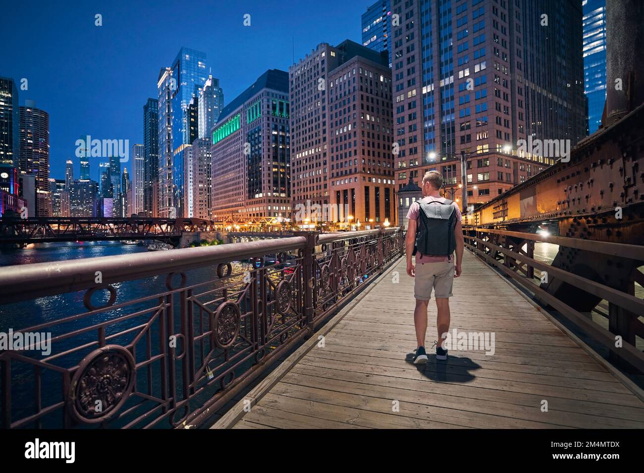 Rear view of man with backpack while walking on bridge and looking ...