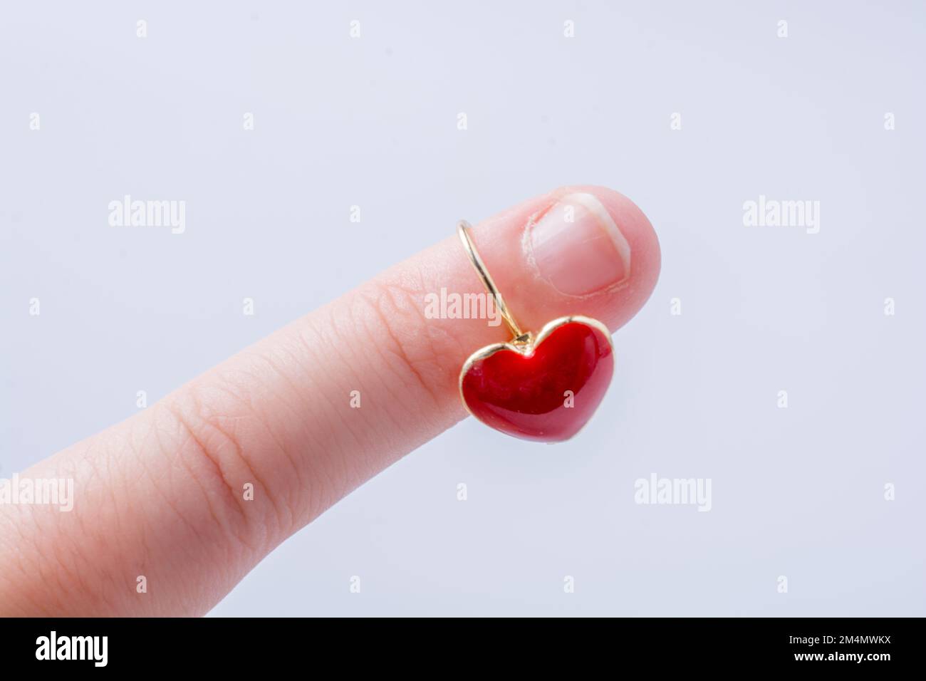 Red color heart shape earring in hand on white Stock Photo - Alamy