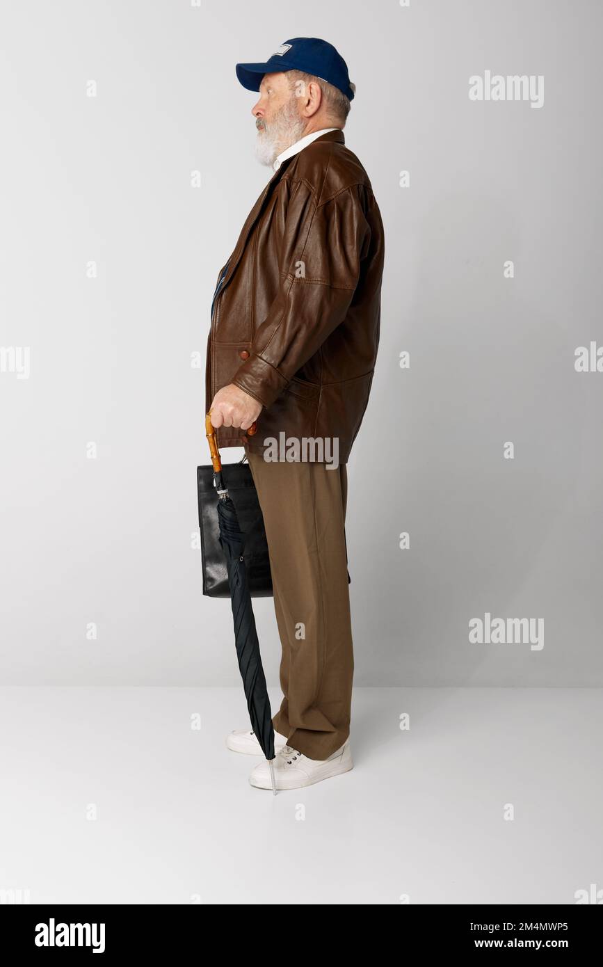 Portrait of senior old man in leather jacket posing with briefcase and ...