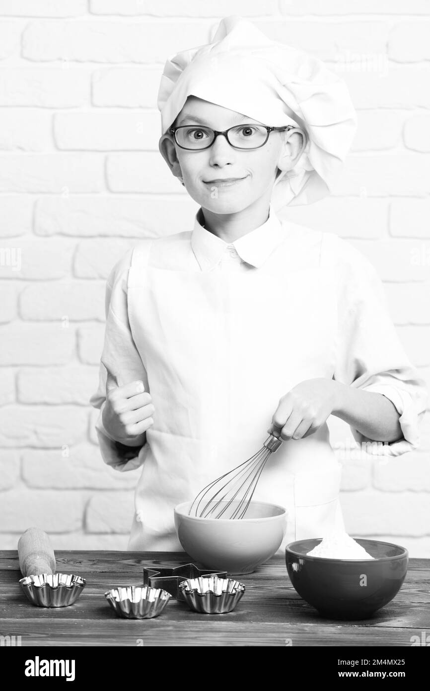 young boy small cute cook chef in white uniform and hat on smiling face ...