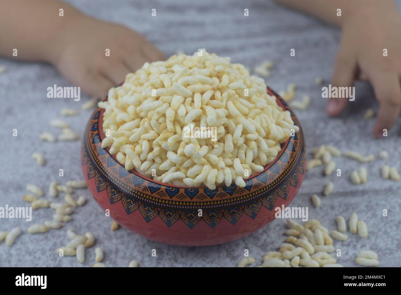 A closeup of a bowl of puffed rice with hands in the background Stock ...