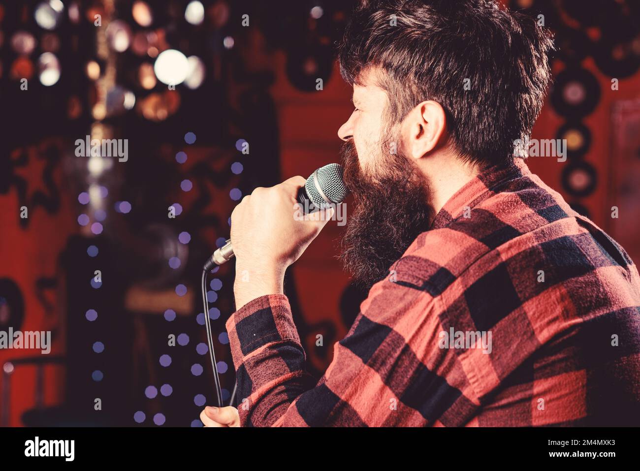 Man in checkered shirt holds microphone, singing song, karaoke club ...