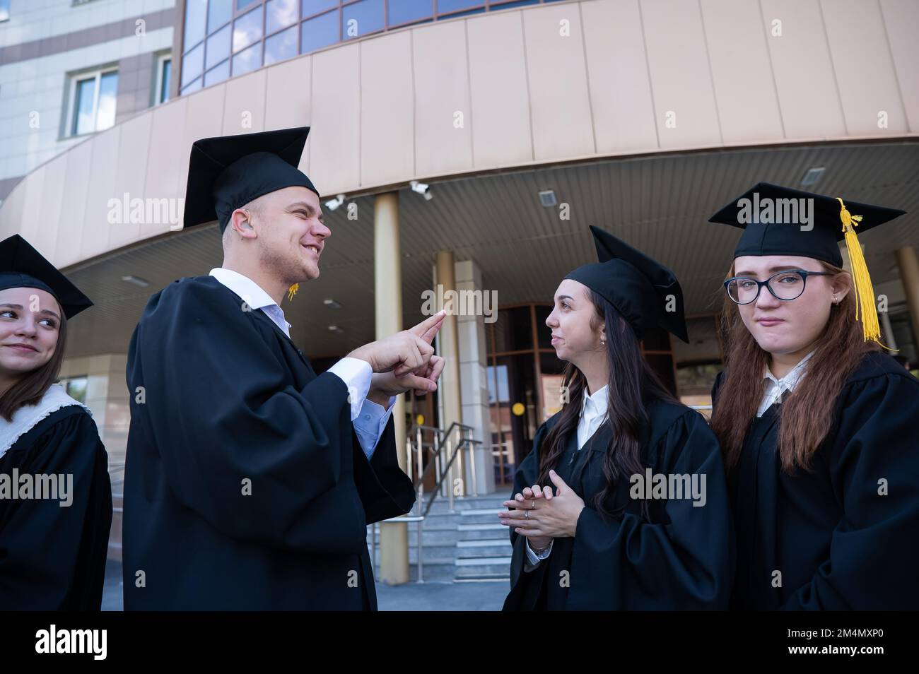 Happy students in graduate gown communicate in sign language Stock ...