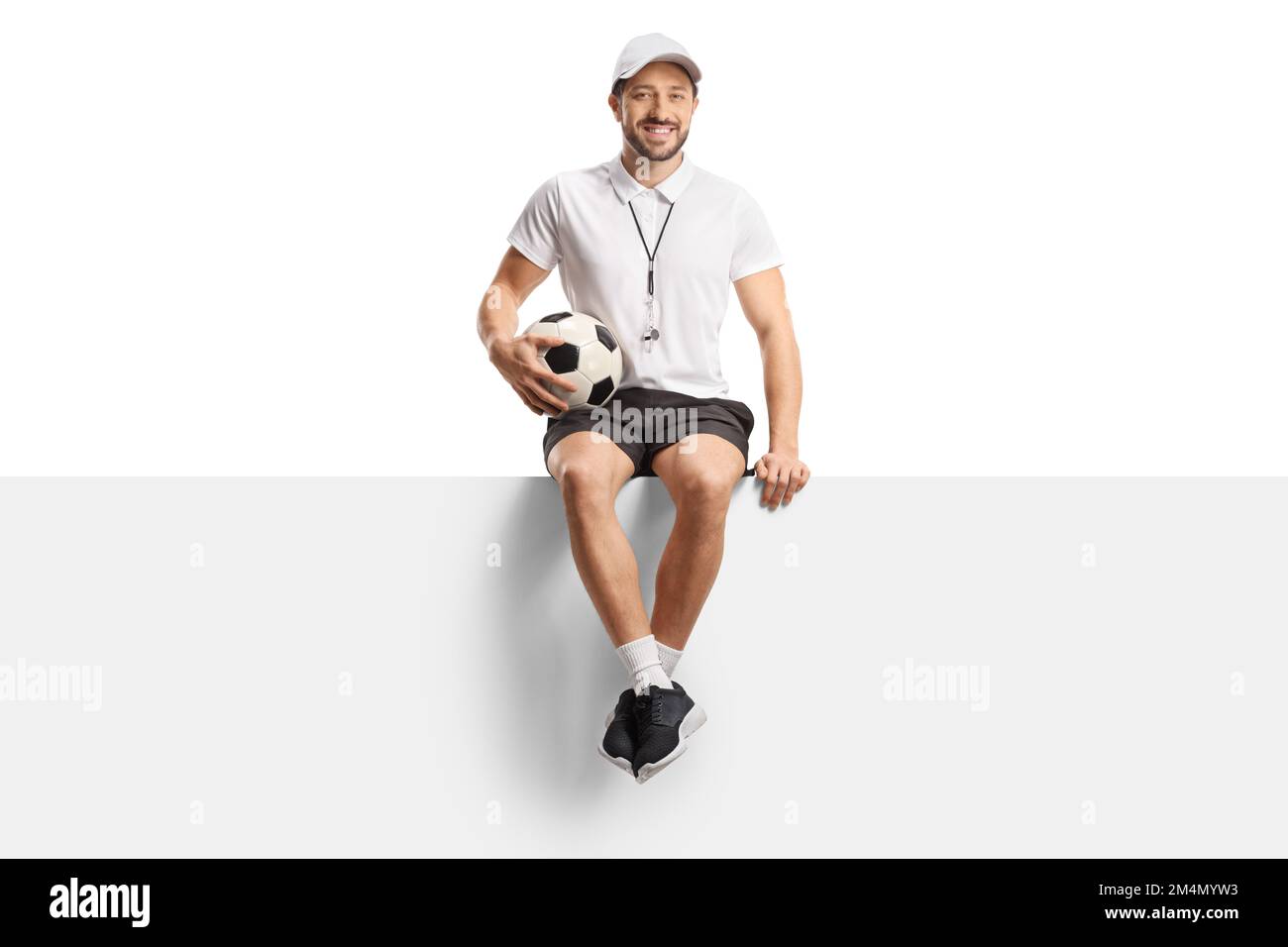 Full length portrait of a football coach holding a ball and sitting on ...