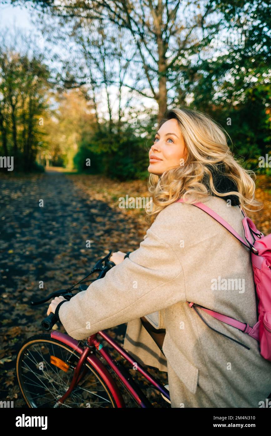 Young attractive caucasian woman ride on bicycle in the park on warm ...