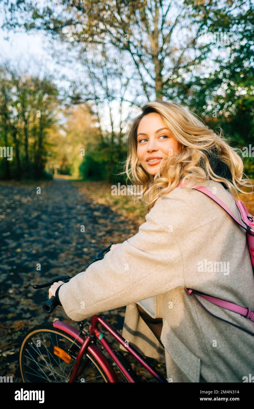 Young attractive caucasian woman ride on bicycle in the park on warm ...